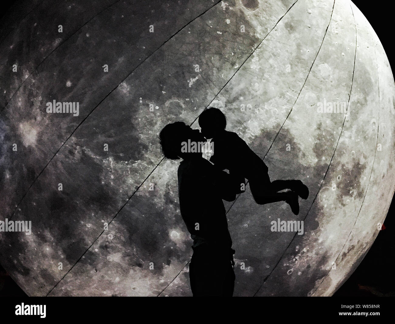 A father kisses his child in front of a giant sphere simulating the ...