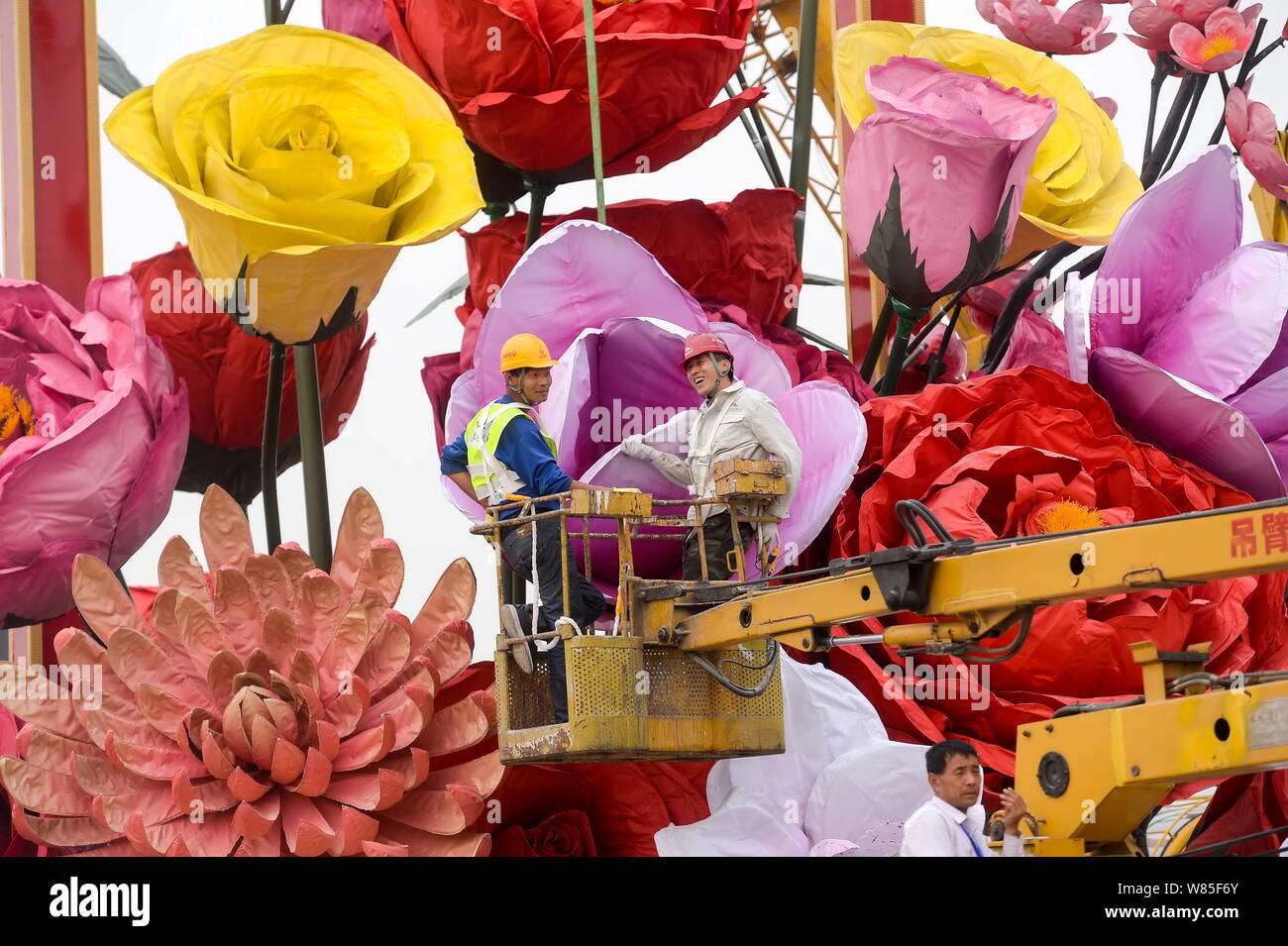 Chinese workers install giant artificial flowers to set up a parterre ...