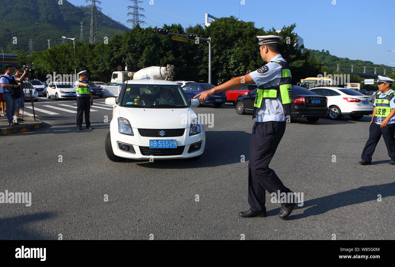 A Chinese police officer stops a car after the driver ran a green light ...