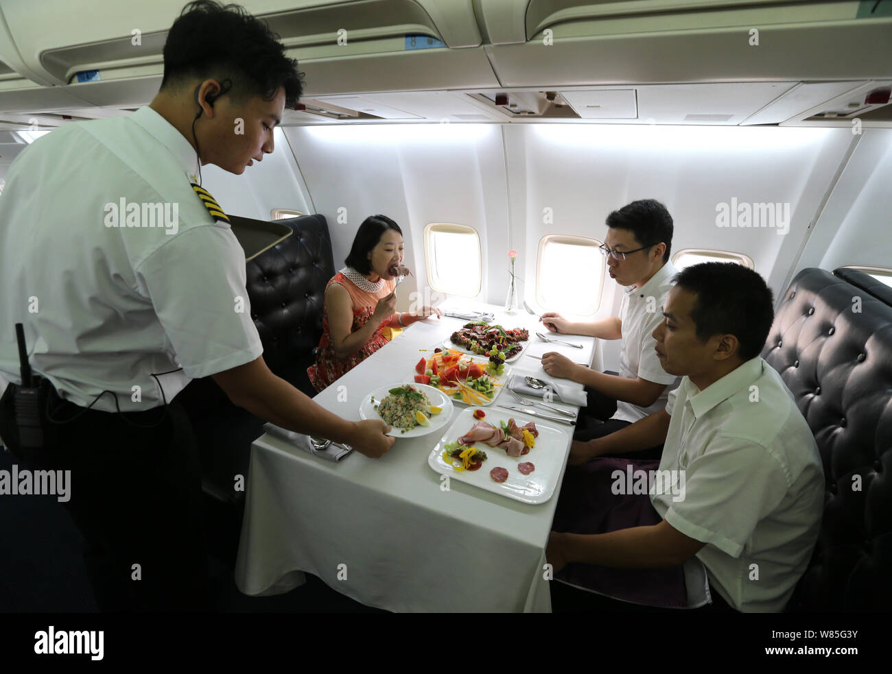 A Chinese waiter dressed in a uniform of pilot serves for customers on ...