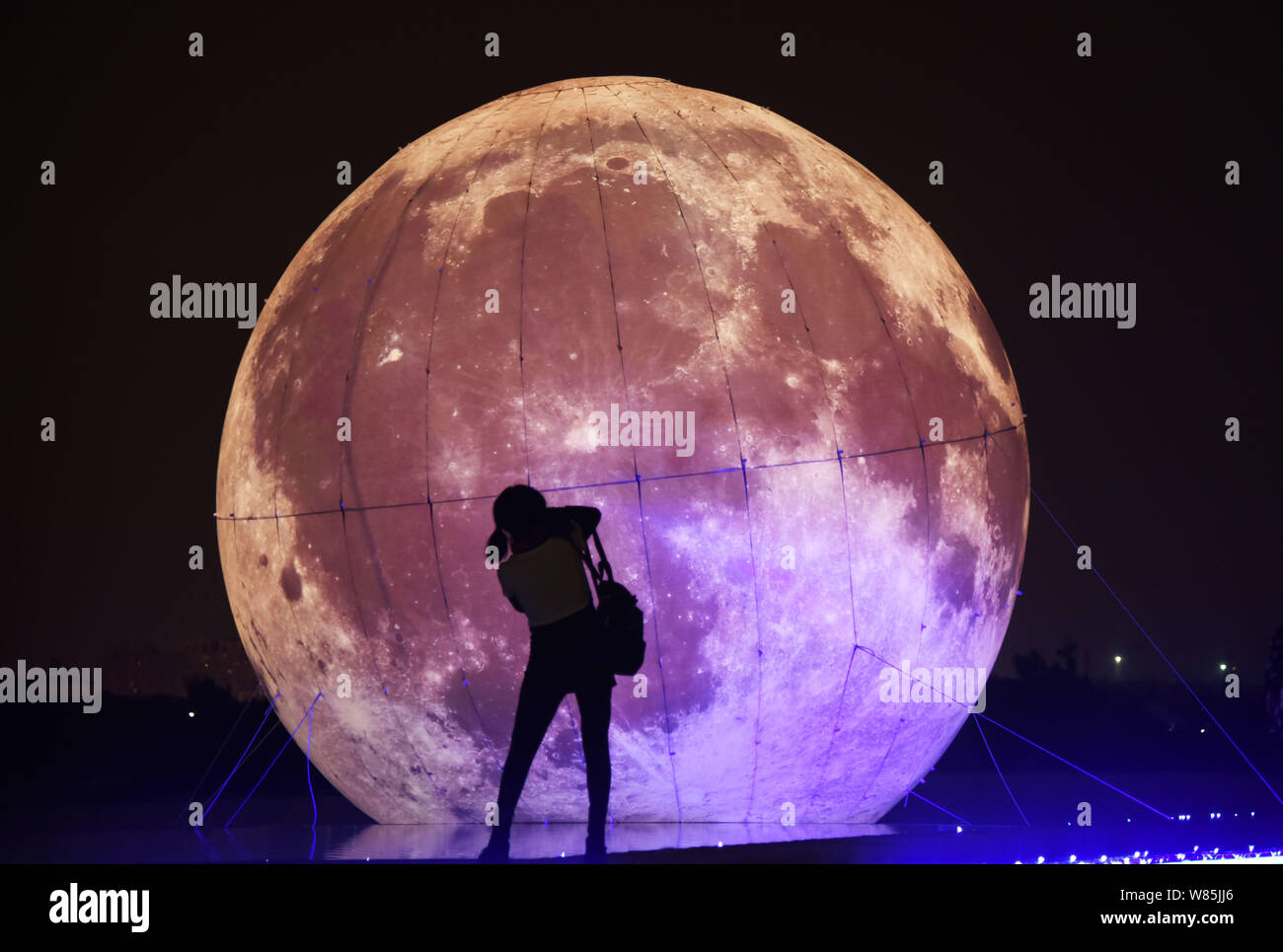 A visitor takes photos of a giant man-made moon to celebrate the ...