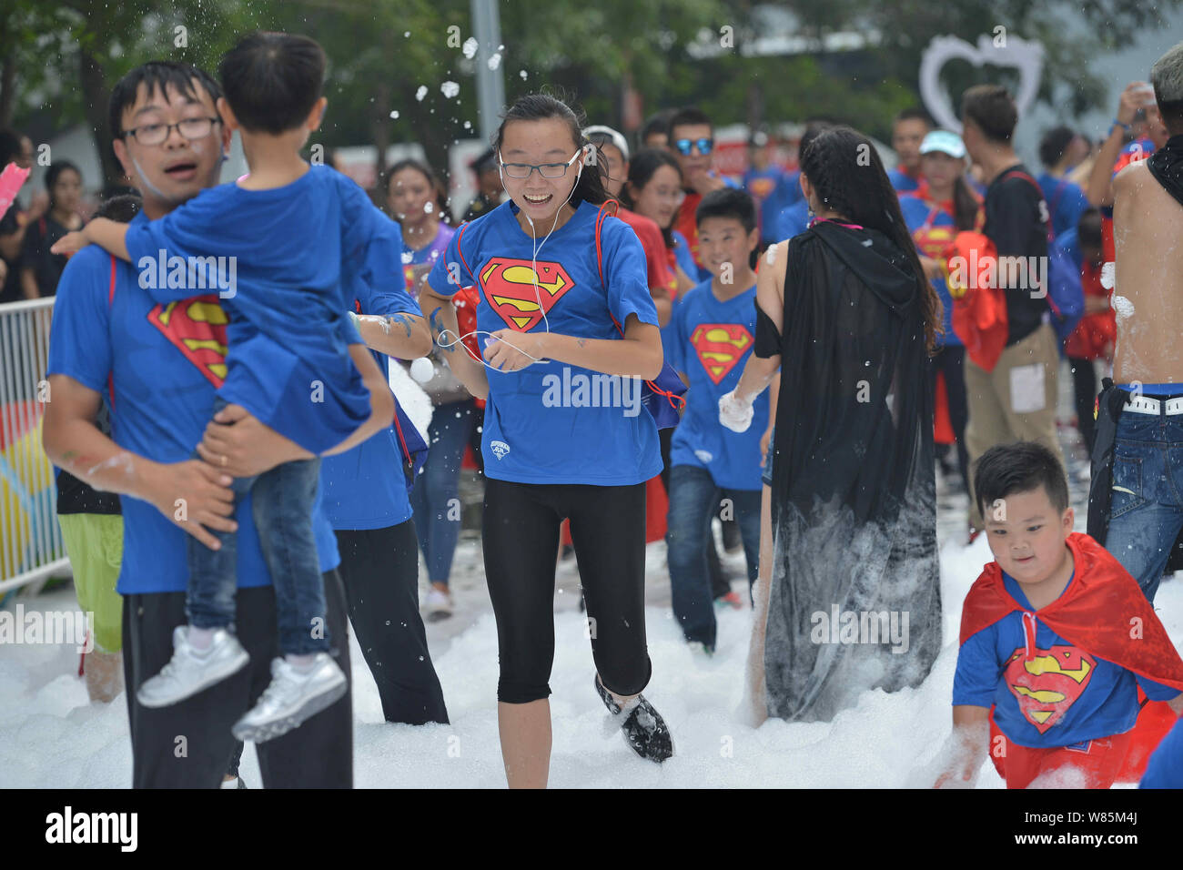 Participants dressed in costumes of Superman have fun with foam during ...