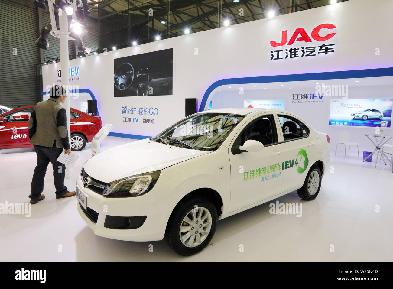 --FILE--A visitor walks past an IEV4 electric car of JAC (Jianghuai ...