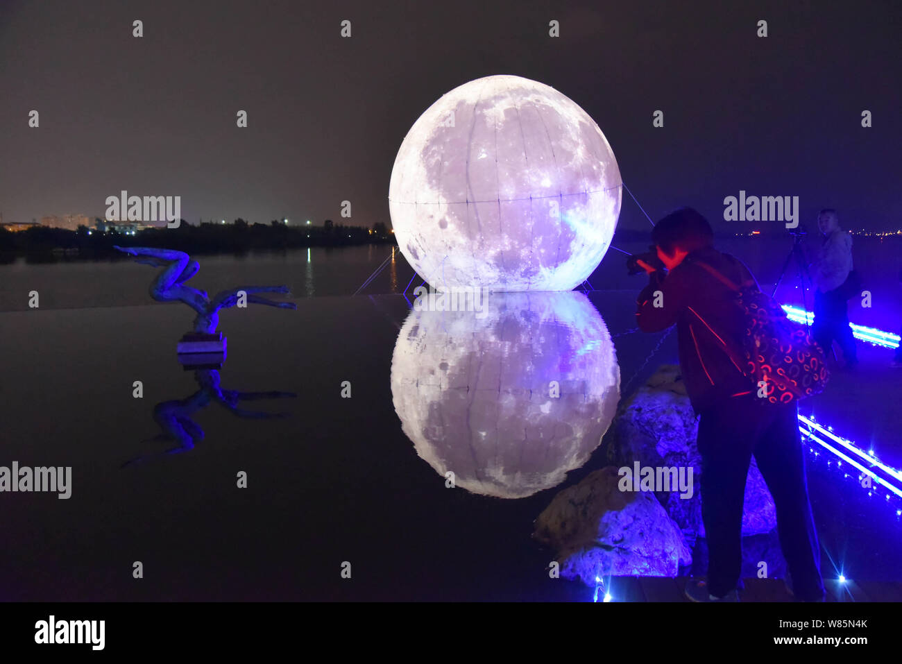 A visitor takes photos of a giant man-made moon to celebrate the ...