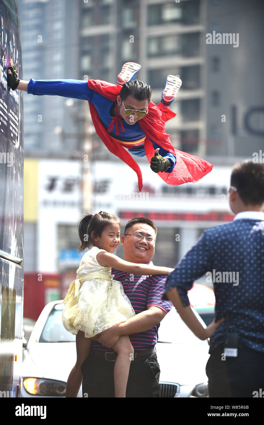 Pedestrians look at Chinese magician Zhou Jieming dressed like Superman ...