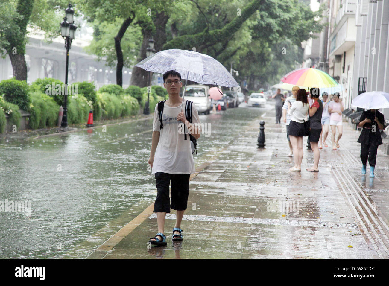 Pedestrians shield themselves with umbrellas from heavy rain caused by ...