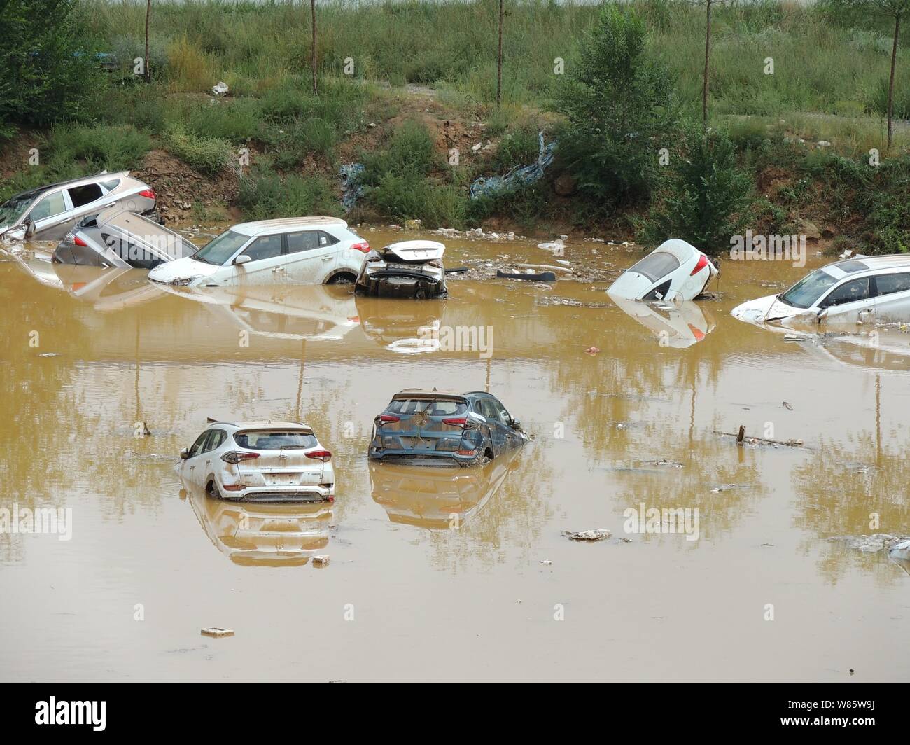 Private cars are submerged in the water after being washed by floods ...