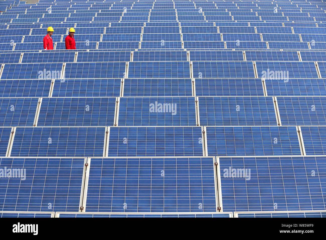 --FILE--Chinese workers check solar panels at a rooftop photovoltaic ...