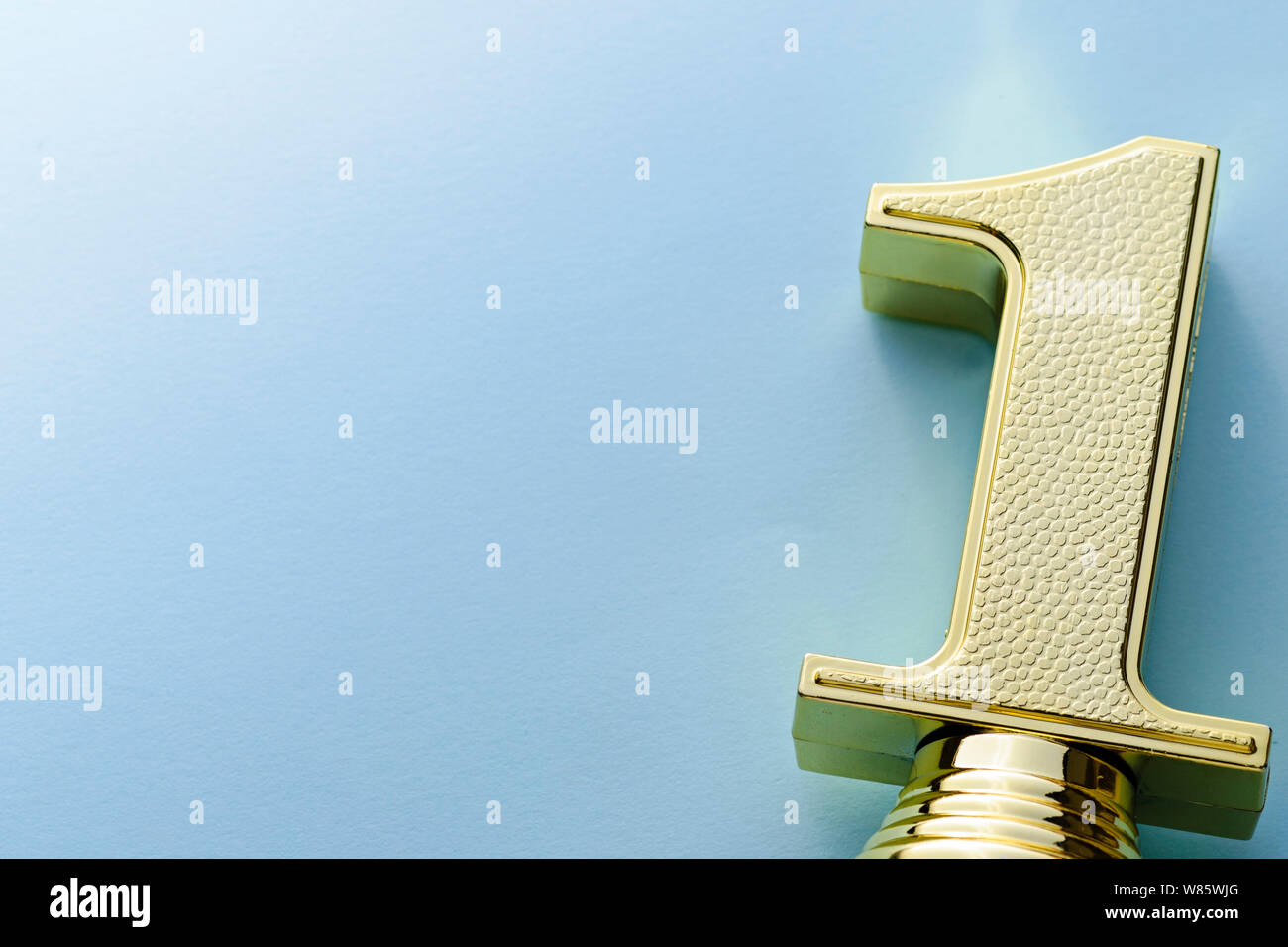 Textured decorative gold winners trophy number one over a grey stdio ...