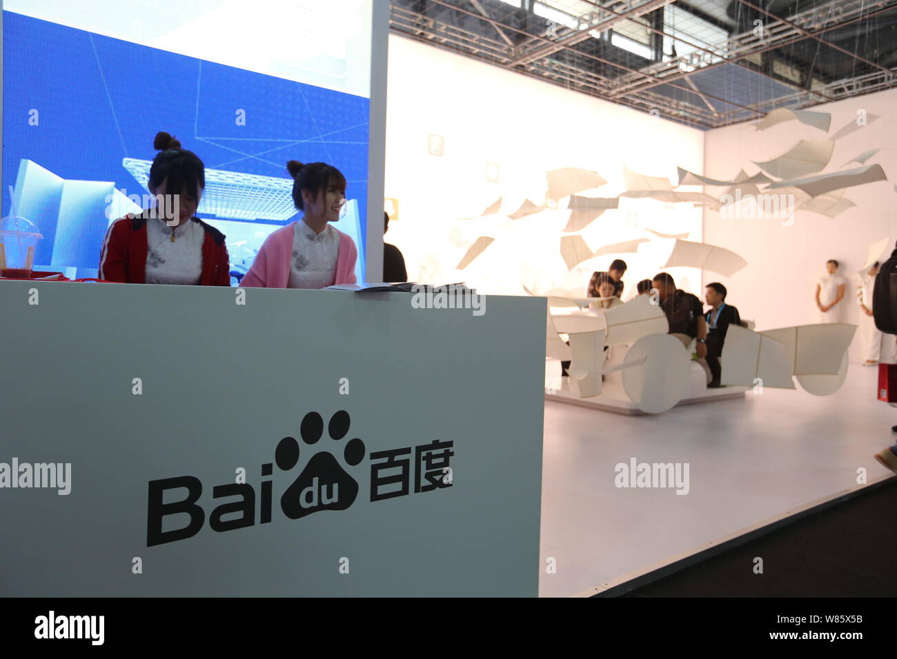 --FILE--Chinese employees are seen at the stand of Baidu during the ...