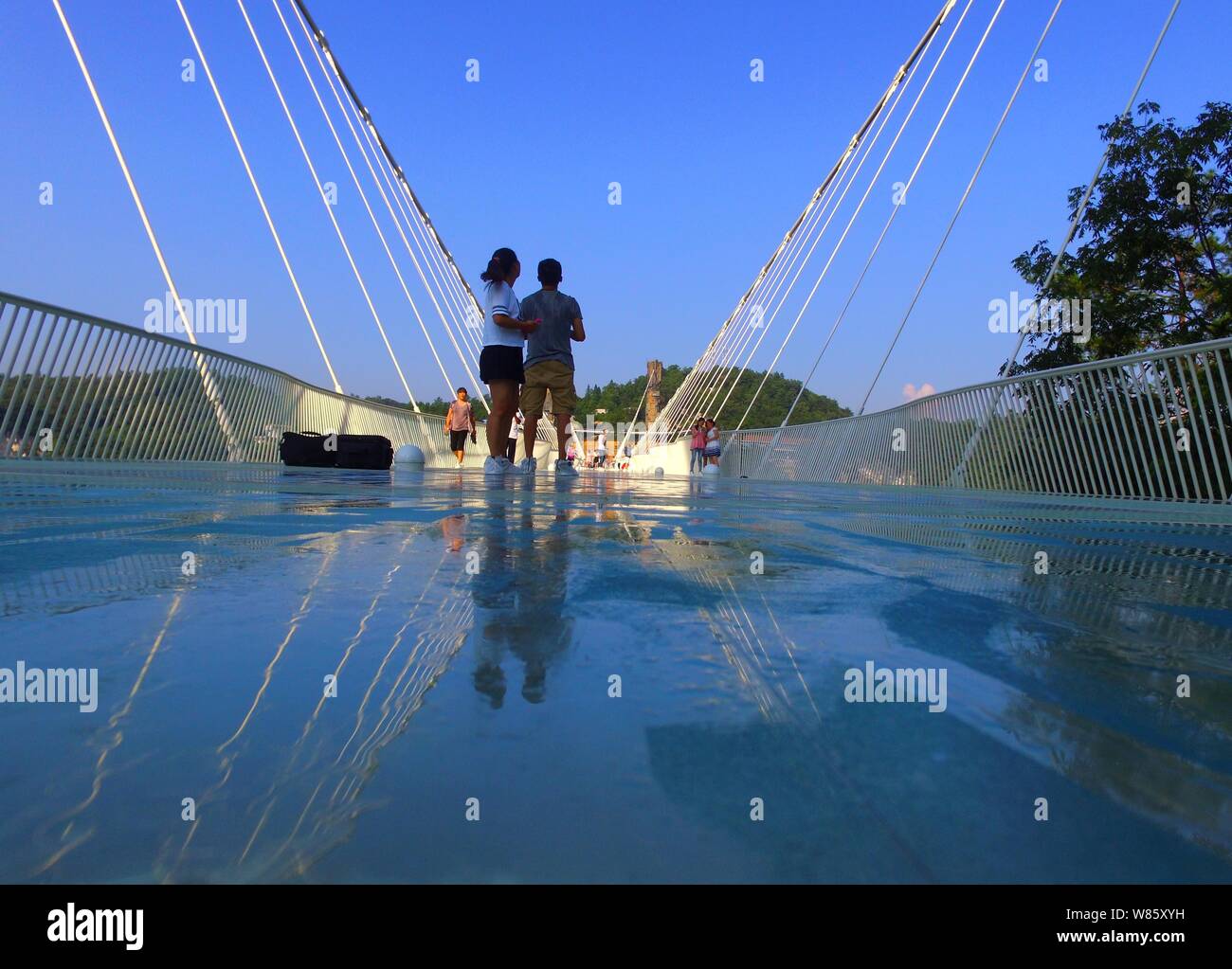 Tourists pose on the world's longest and highest glass-bottomed bridge ...