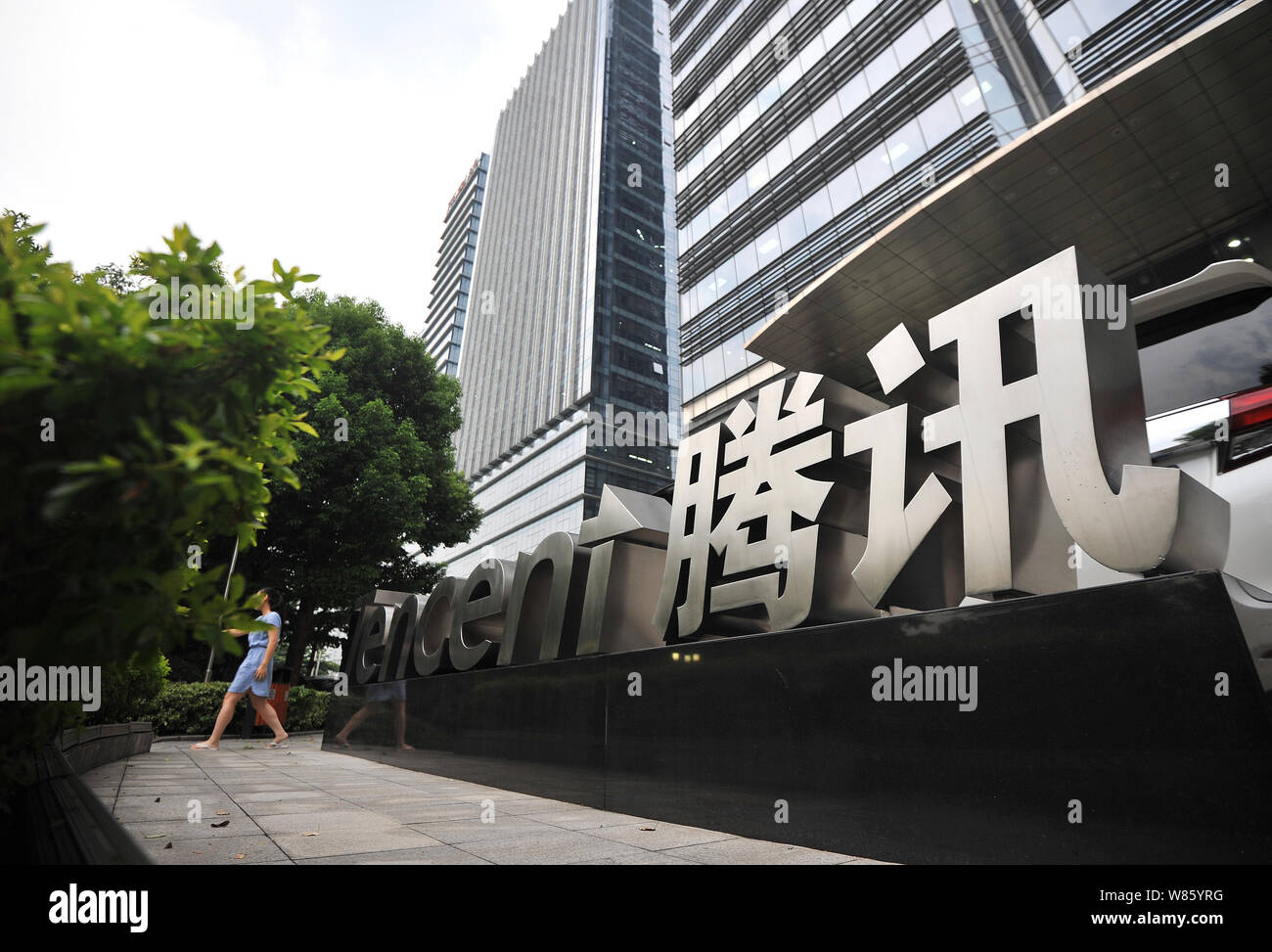 --FILE--A pedestrian walks past the logo of Tencent in front of the ...