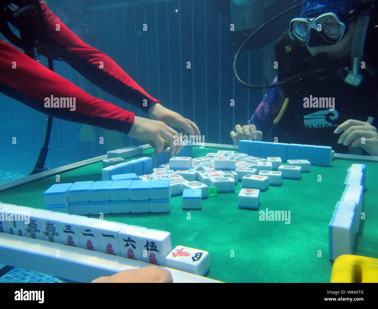 Young Chinese people equipped with diving gears play mahjong underwater ...