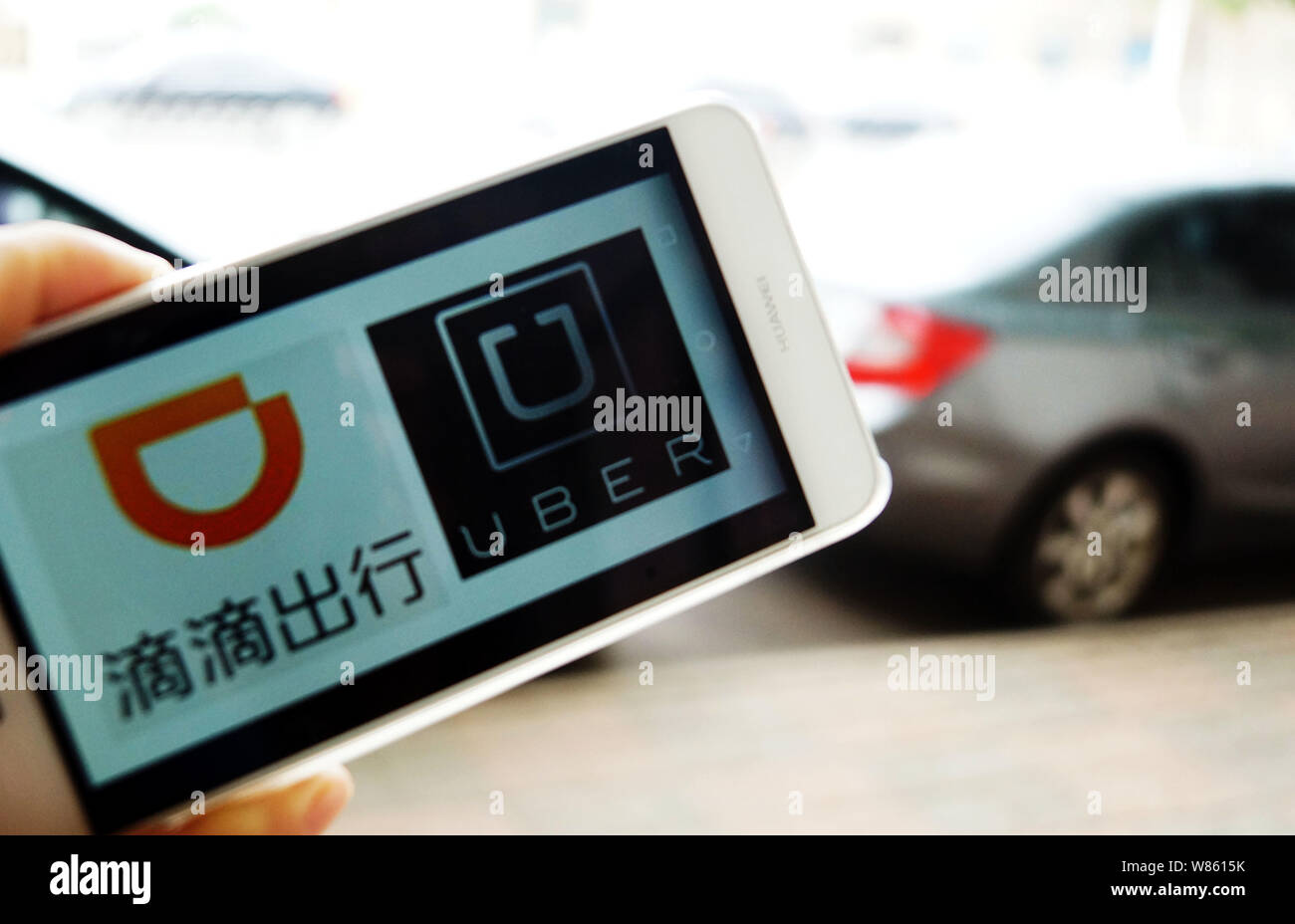 A Chinese mobile phone user shows the logos of taxi-hailing apps Didi ...