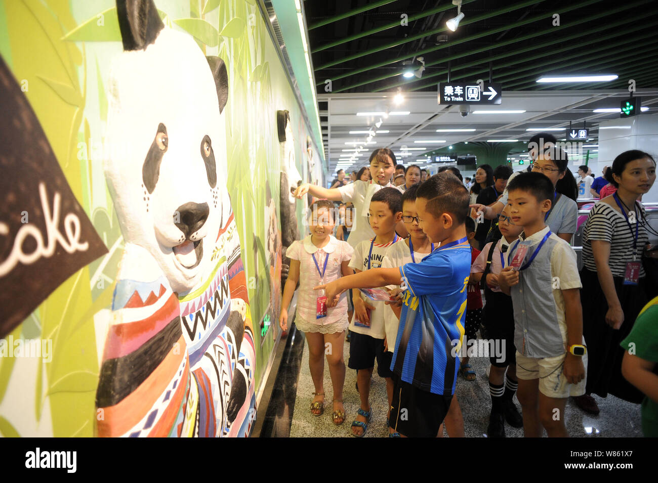 Children look at a giant panda pictured at a panda-themed metro station ...