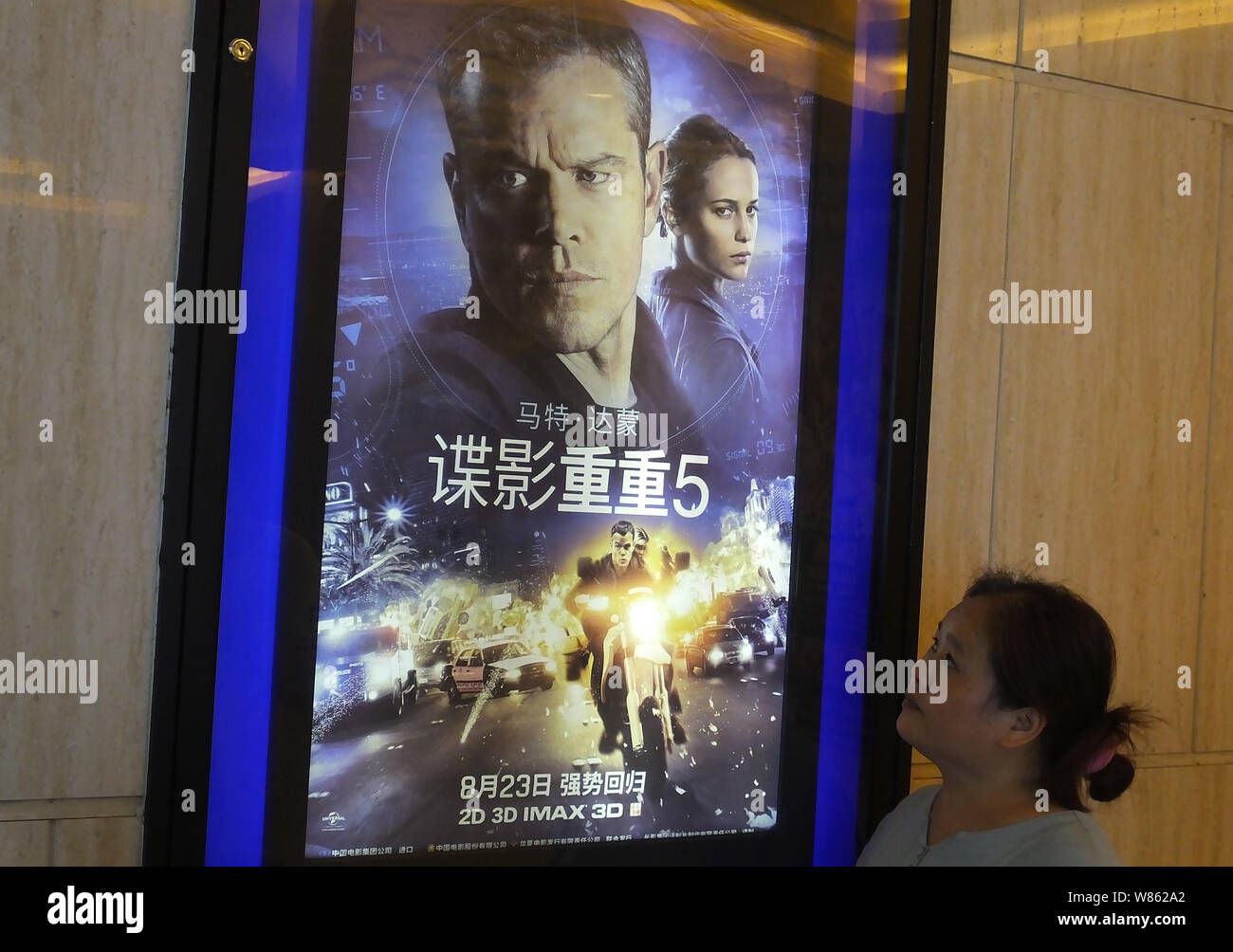 A Chinese filmgoer looks at a poster of the movie "Jason Bourne" at a ...