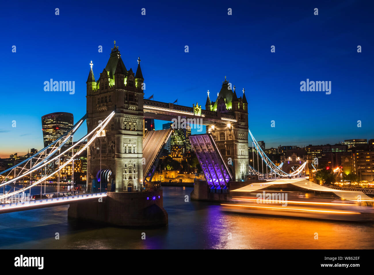 England, London, Tower Bridge open at night with Boat Passing through ...
