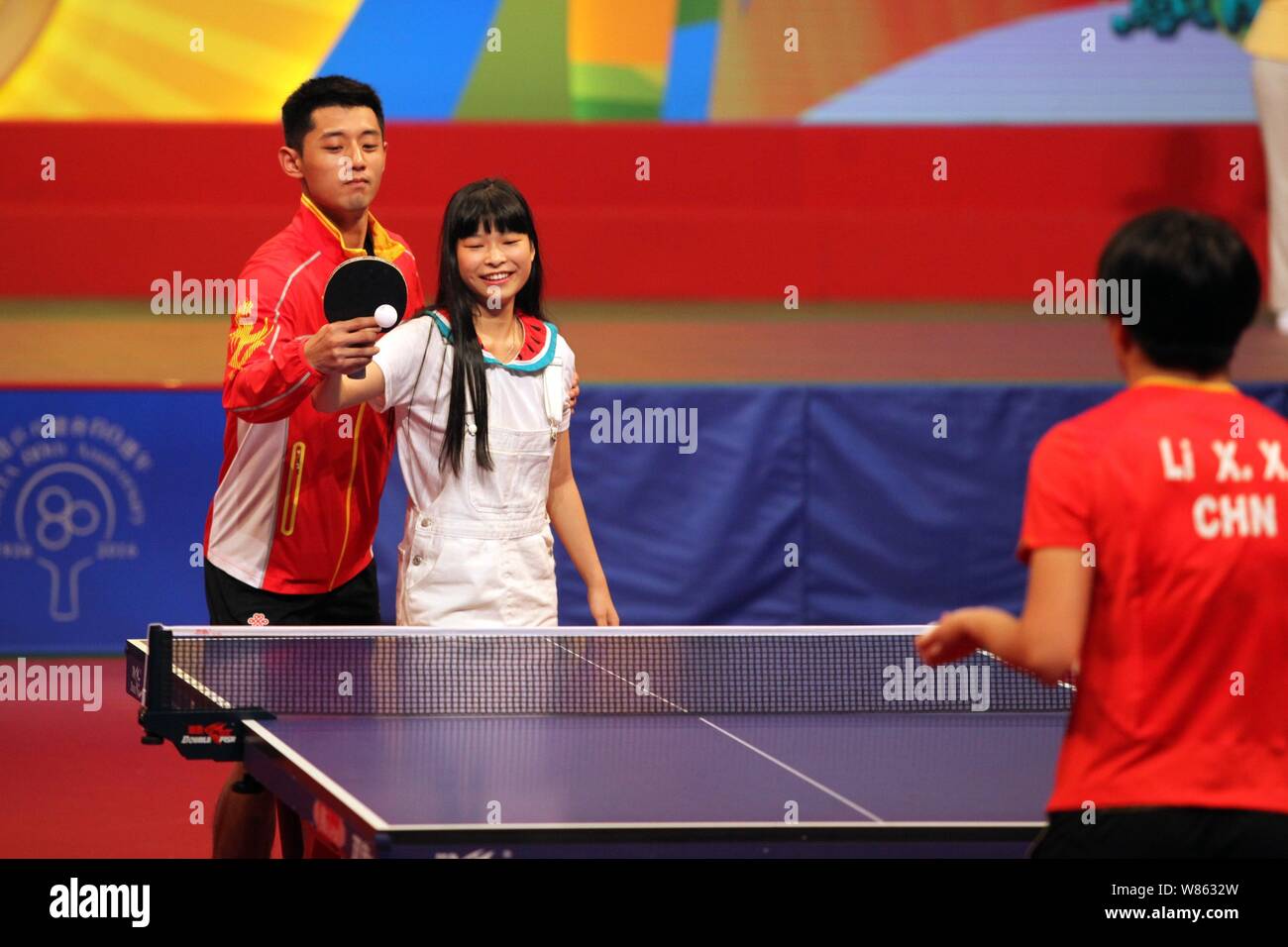 Chinese table tennis player Zhang Jike, back, instructs a fan to play table tennis at a ...