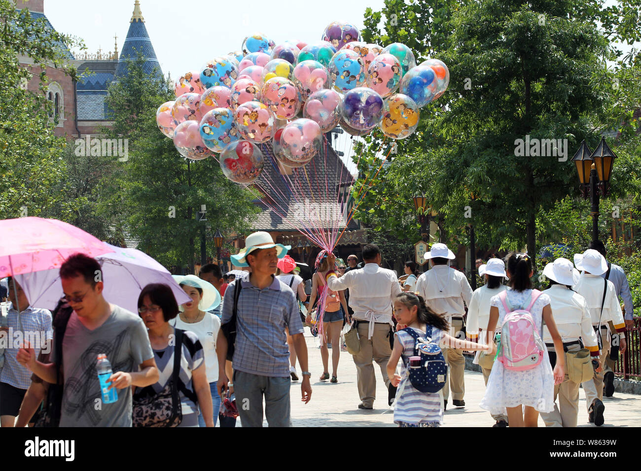 --FILE--Tourists walk past an employee selling Mickey Mouse and Minnie ...