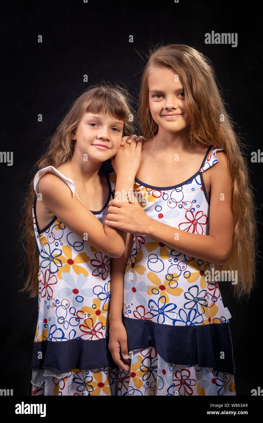 Two sisters of different ages on a black background Stock Photo - Alamy
