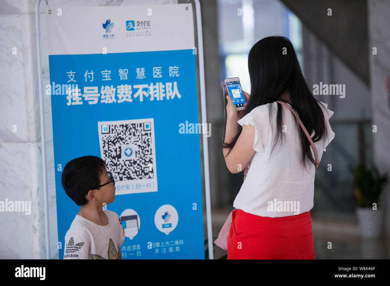 --FILE--A mother uses her smartphone to scan a QR code to register or ...