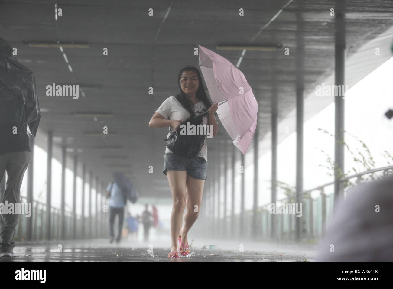A Chinese commuter struggles with his umbrella in heavy rain and strong ...