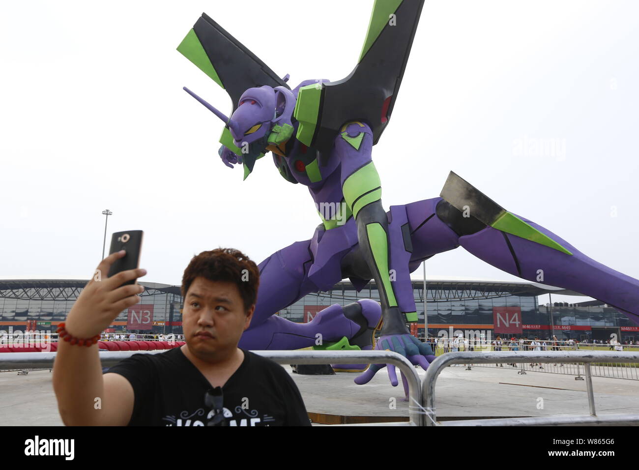 A visitor takes a selfie in front of a giant model of Evangelion from ...