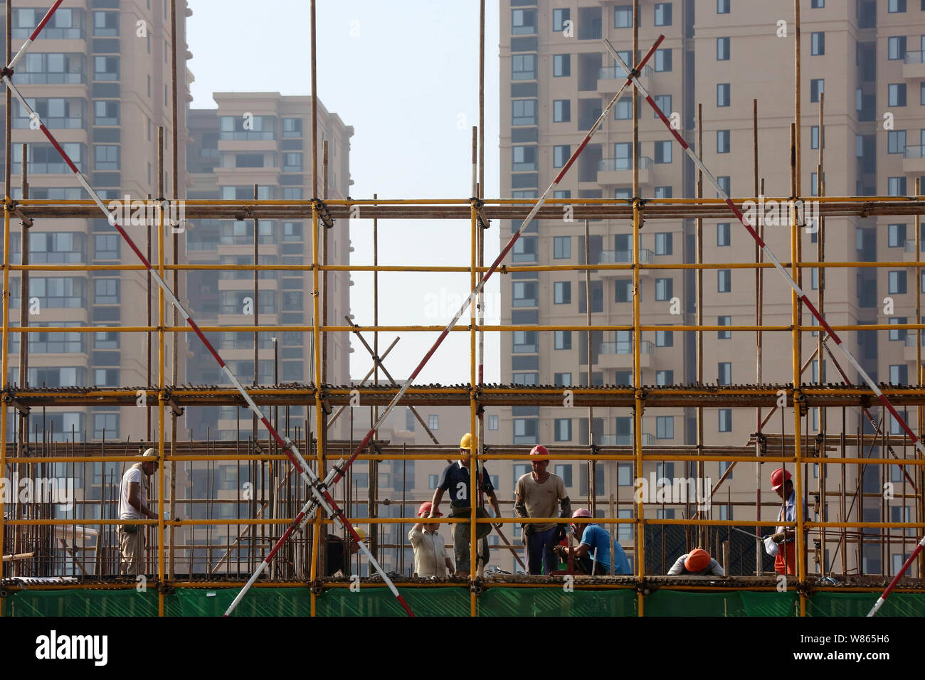 Chinese migrant workers construct a high-rise apartment building at the ...
