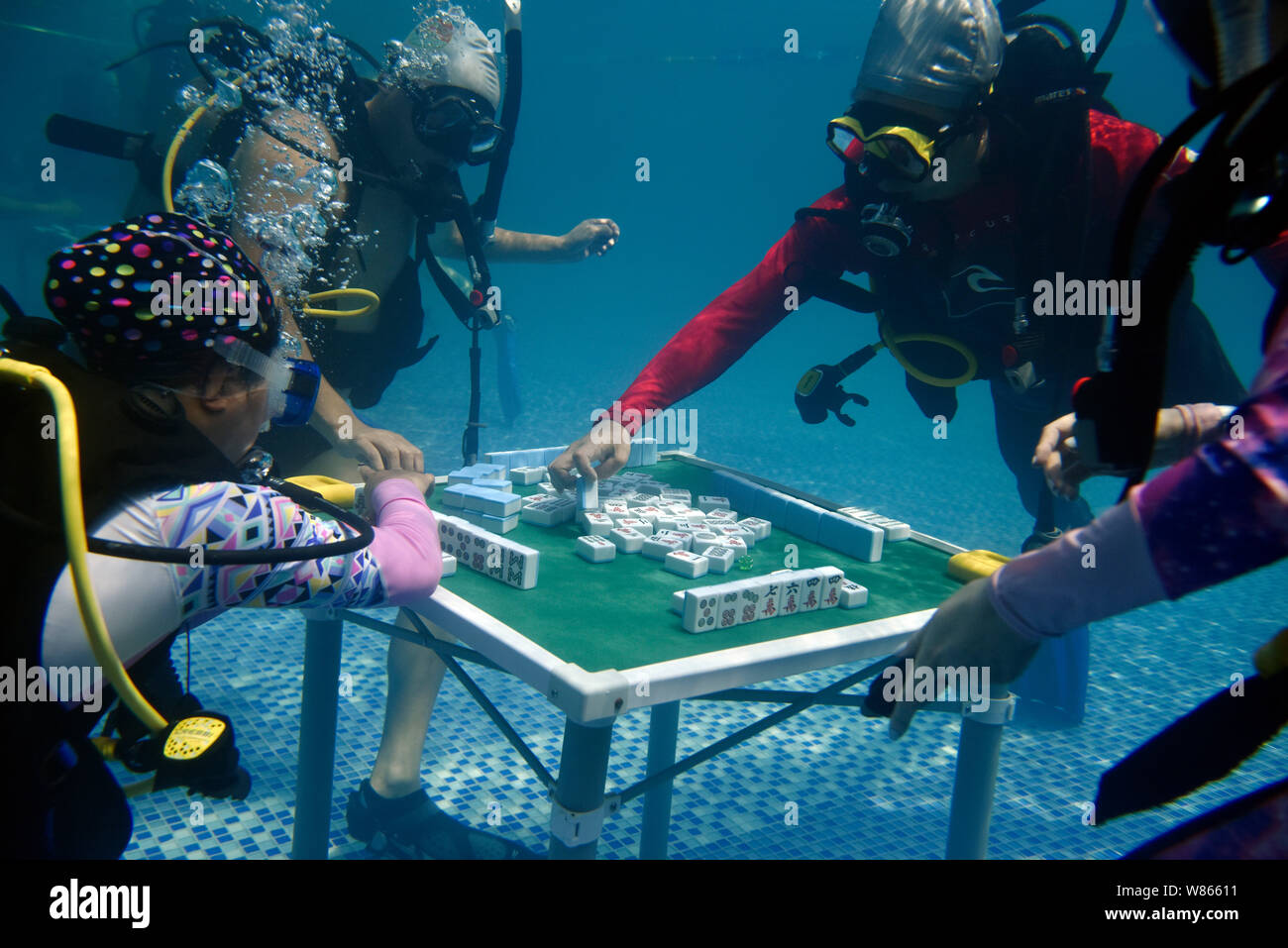 Young Chinese people equipped with diving gears play mahjong underwater ...