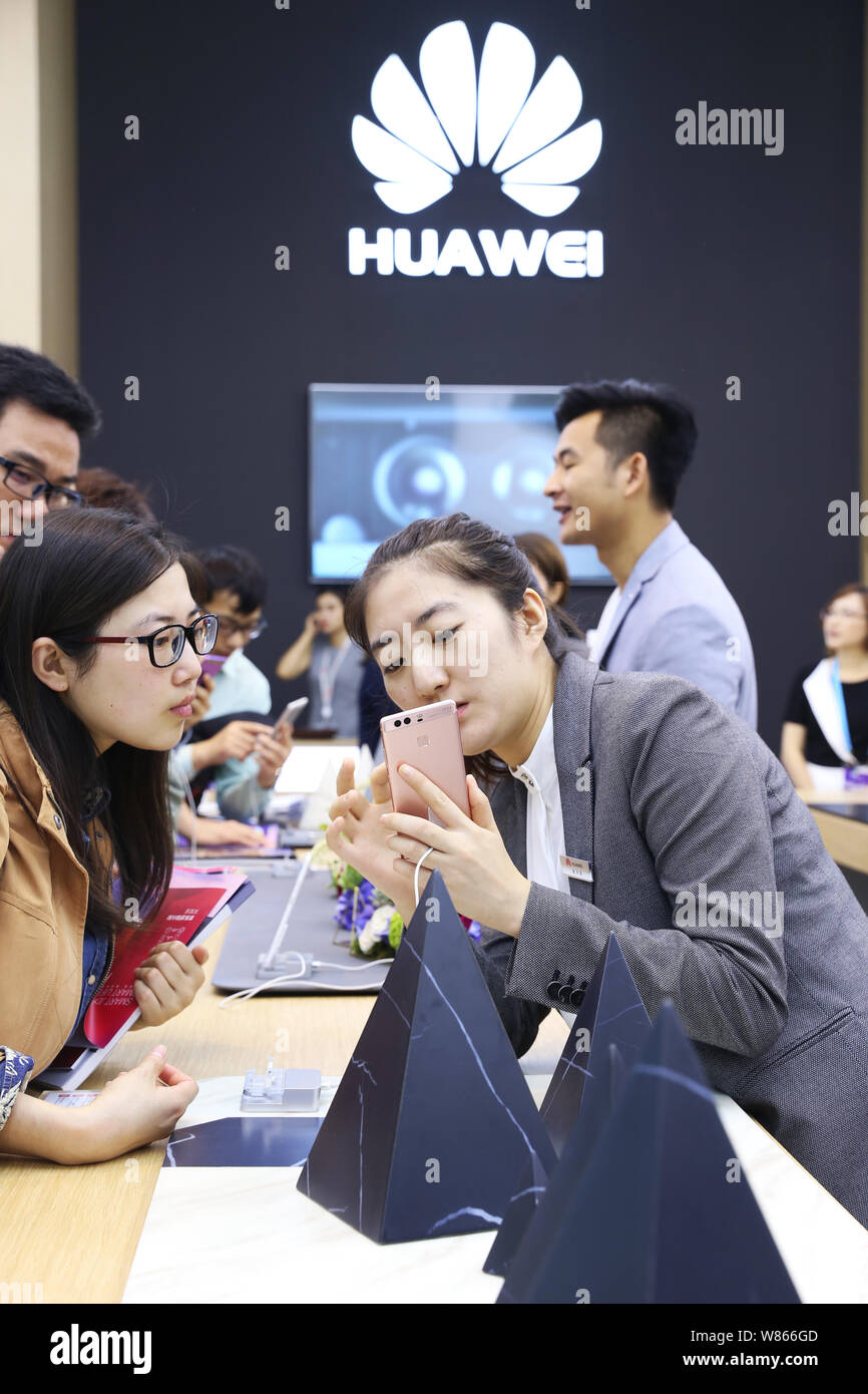 --FILE--A Chinese employee introduces a Huawei smartphone to a visitor ...