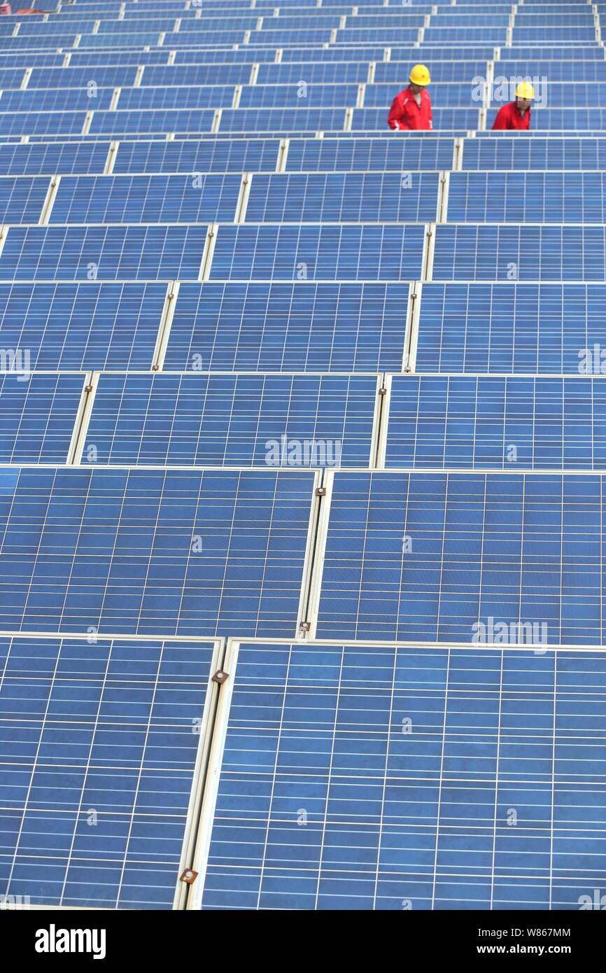 --FILE--Chinese workers check solar panels at a rooftop photovoltaic ...