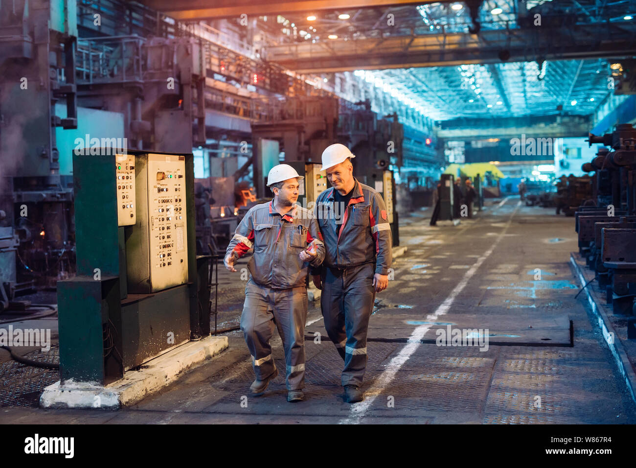 Workers in the steel mill. Factory worker takes a sample for metal ...