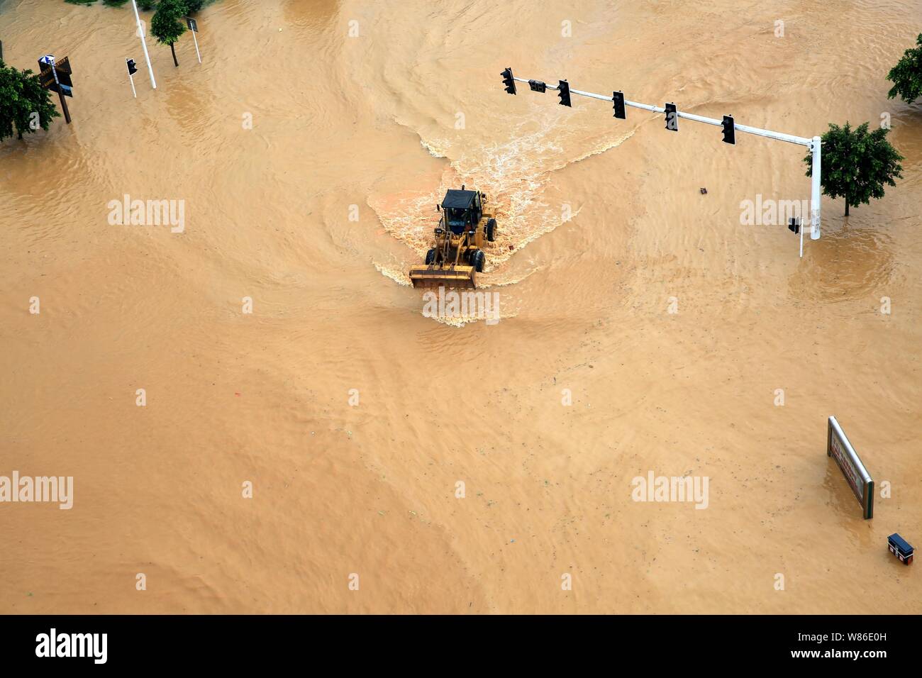 A wheel loader travels on a flooded road caused by heavy rain in ...