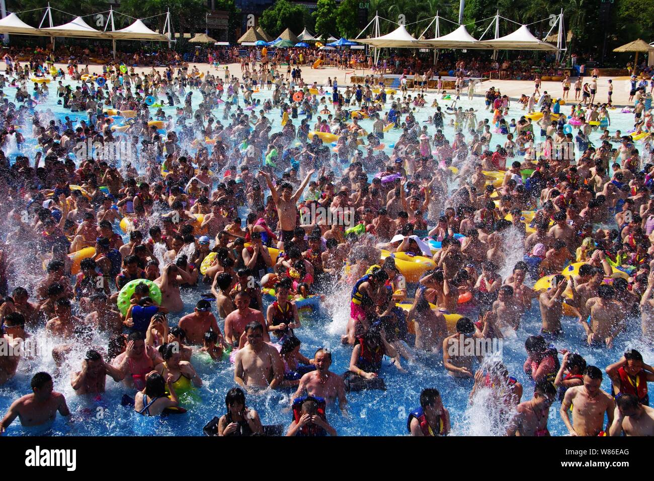 Holidaymakers crowd a swimming pool to cool off on a scorching day in ...