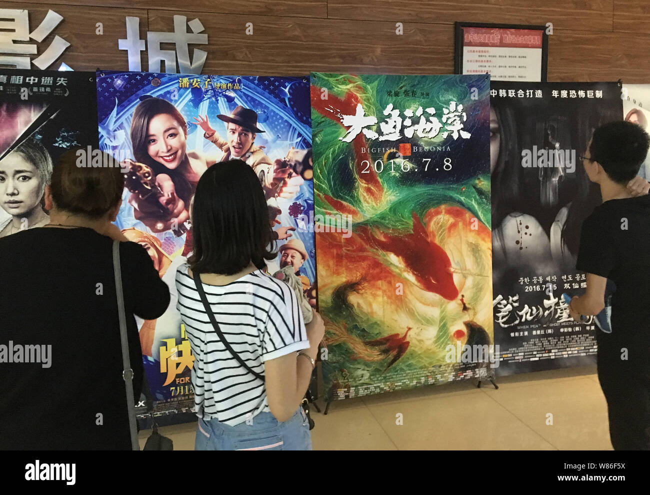 A Chinese filmgoer looks at posters of movies at a cinema in Yichang ...
