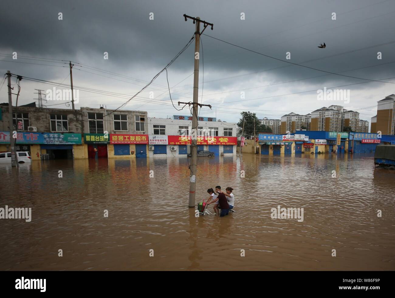 A Chinese family of three braves floodwaters on a bike on a flooded ...