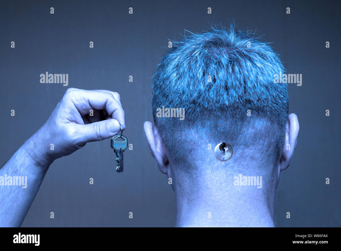 A man with a keyhole in the back of his head holds keys in a raised ...