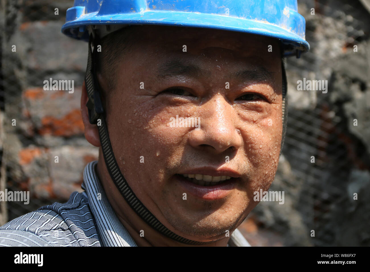 A Chinese worker sweats all over his face as he labors at a ...