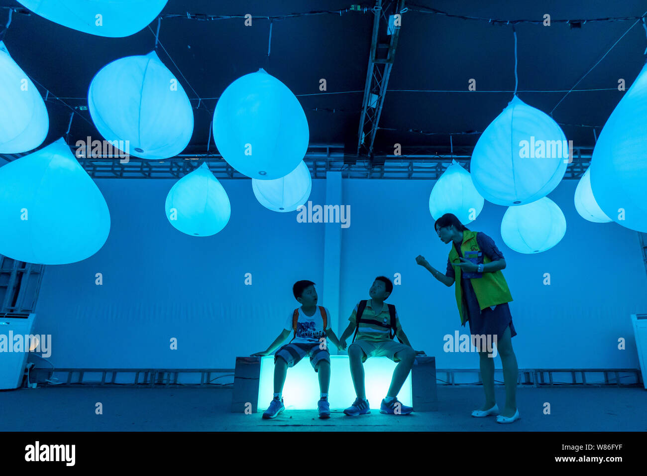 Visitors sit under illuminated giant raindrop-shaped installations at ...