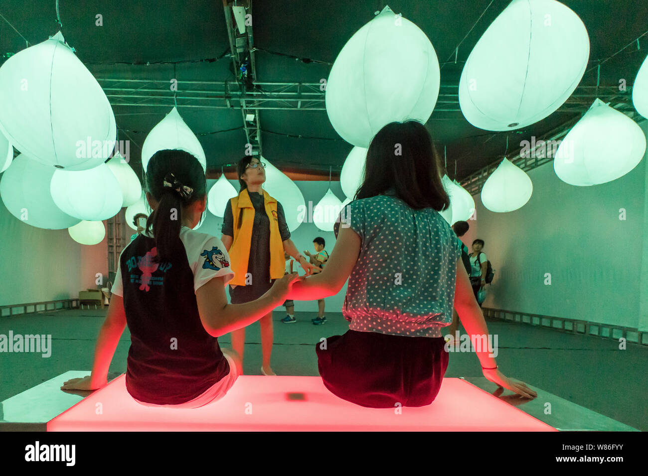 Visitors sit under illuminated giant raindrop-shaped installations at ...