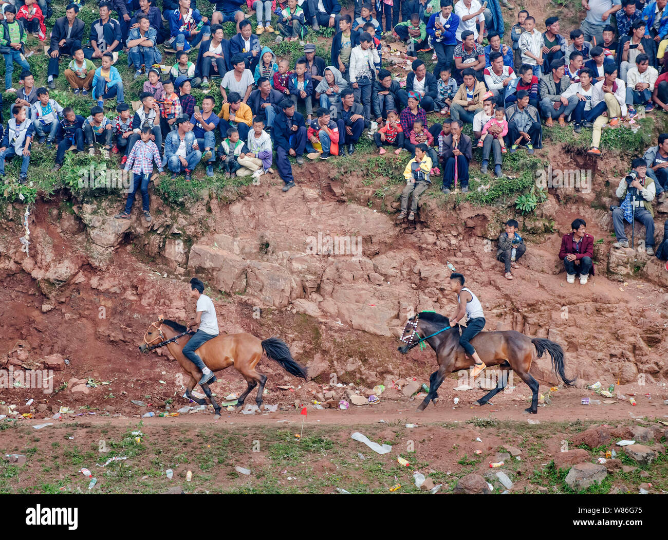 Visitors and people of Yi ethnical minority watch a horse racing during ...