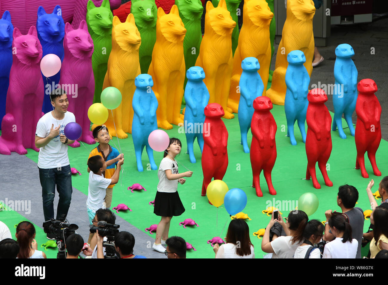 People take pictures or look at plastic animals made from recyclable ...