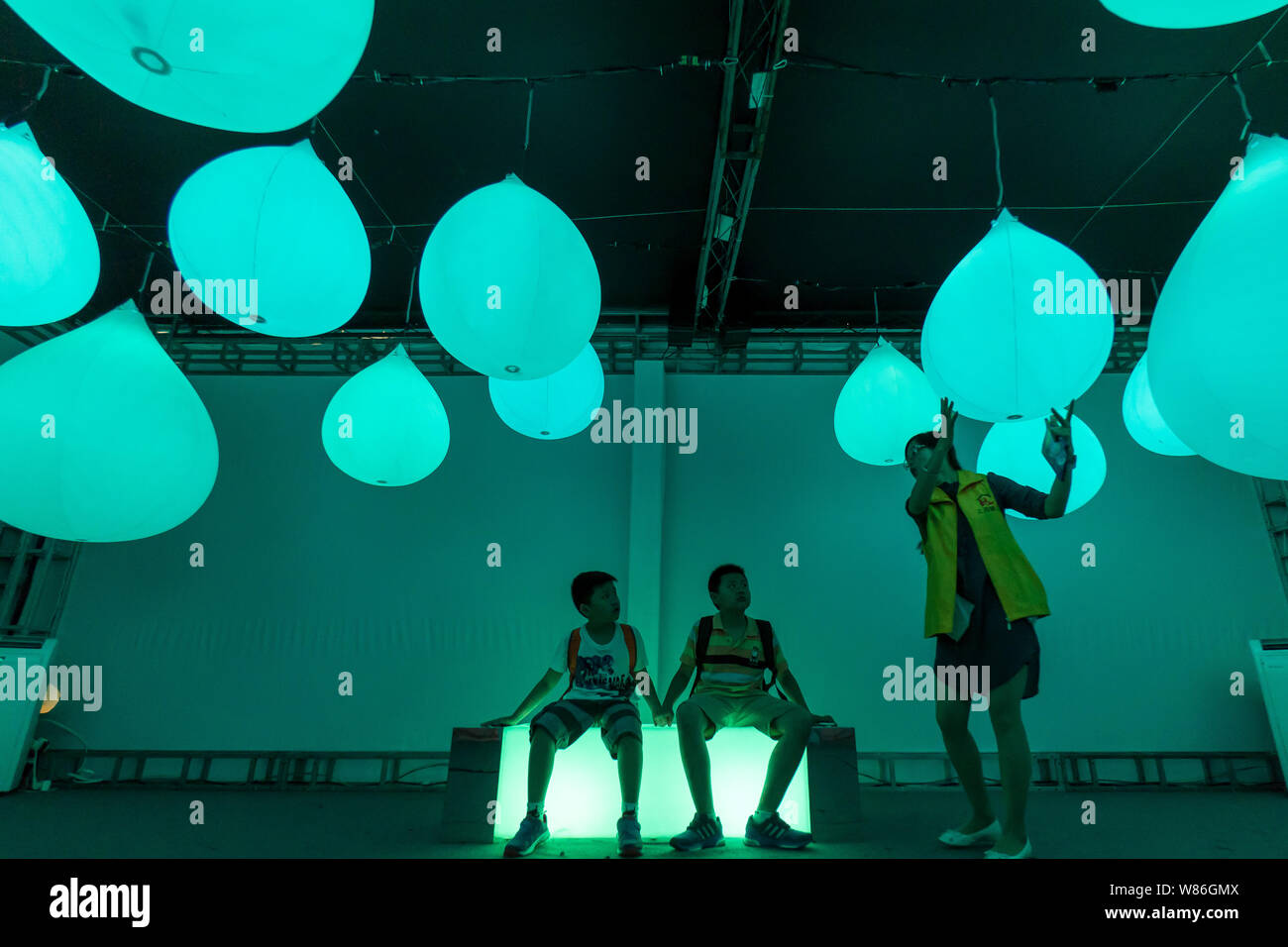 Visitors sit under illuminated giant raindrop-shaped installations at ...