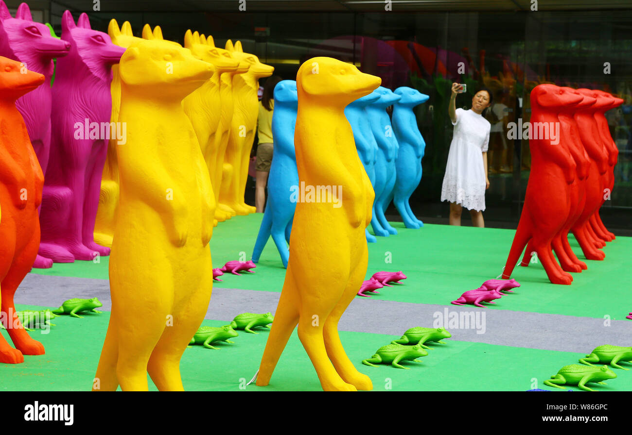 A woman takes a picture of plastic animals made from recyclable plastic ...