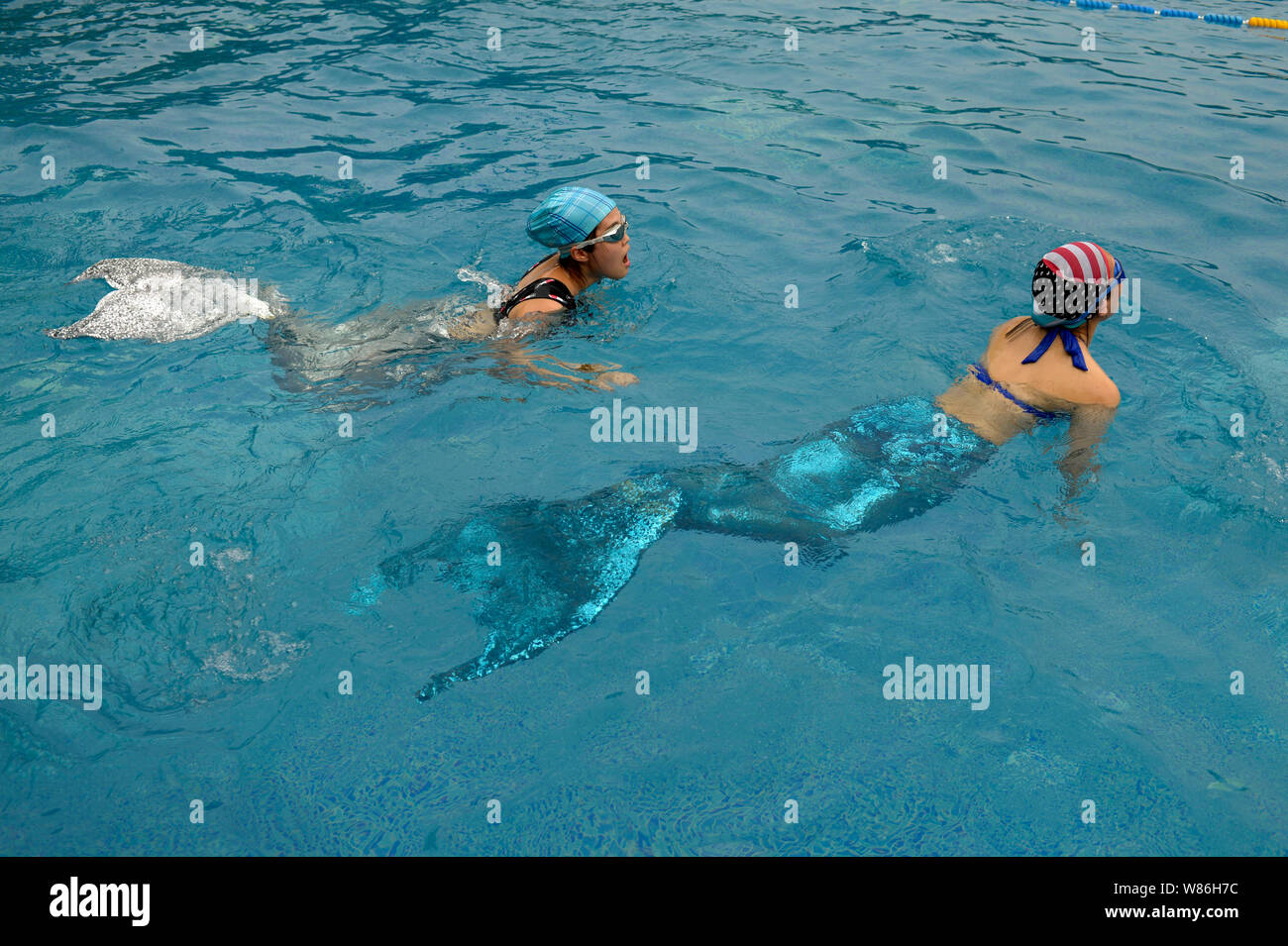 Young Chinese women dressed in mermaid costumes swim in the pool to ...