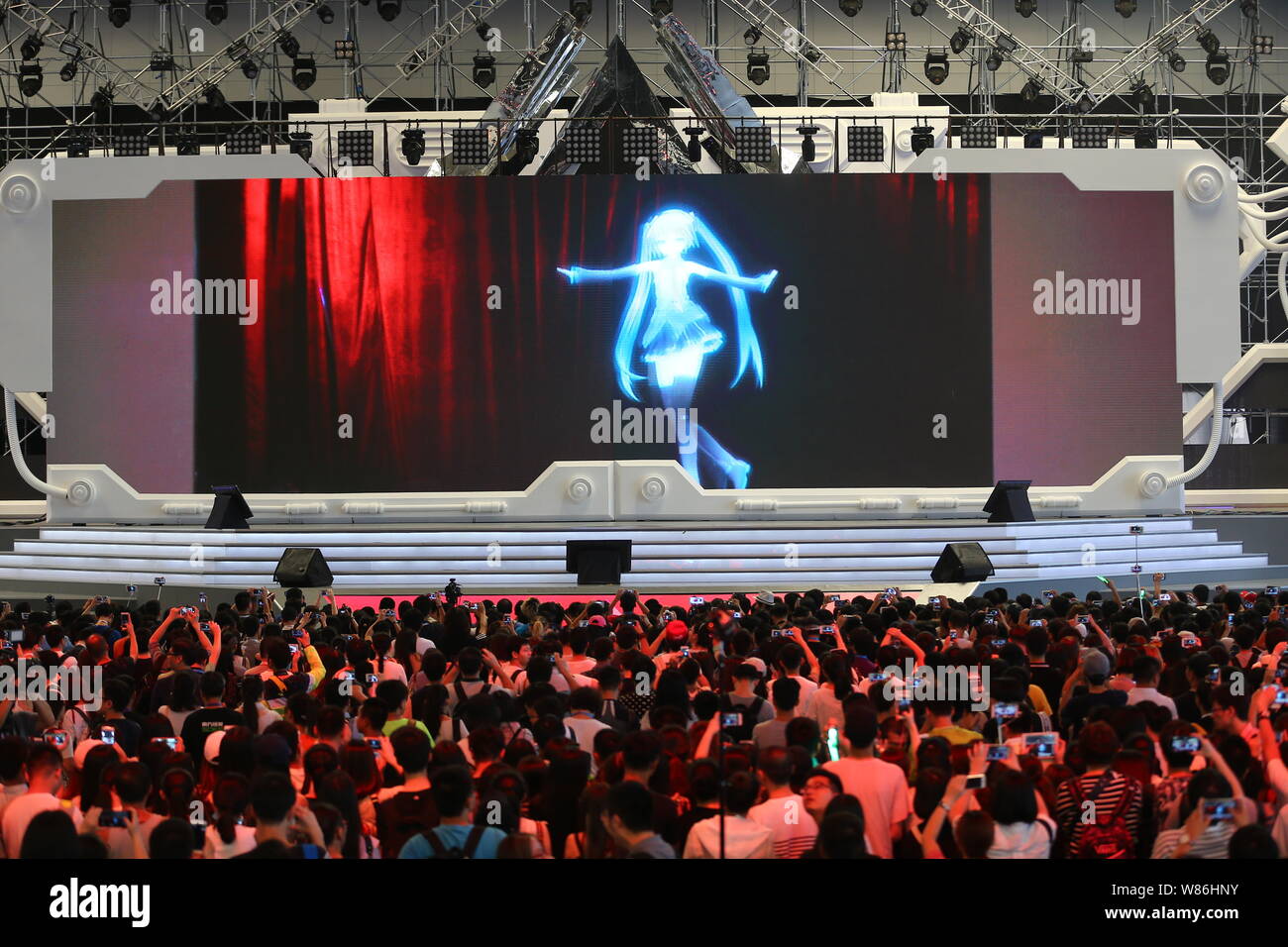 A crowd of visitors watch a performance of Hatsune Miku, a humanoid ...
