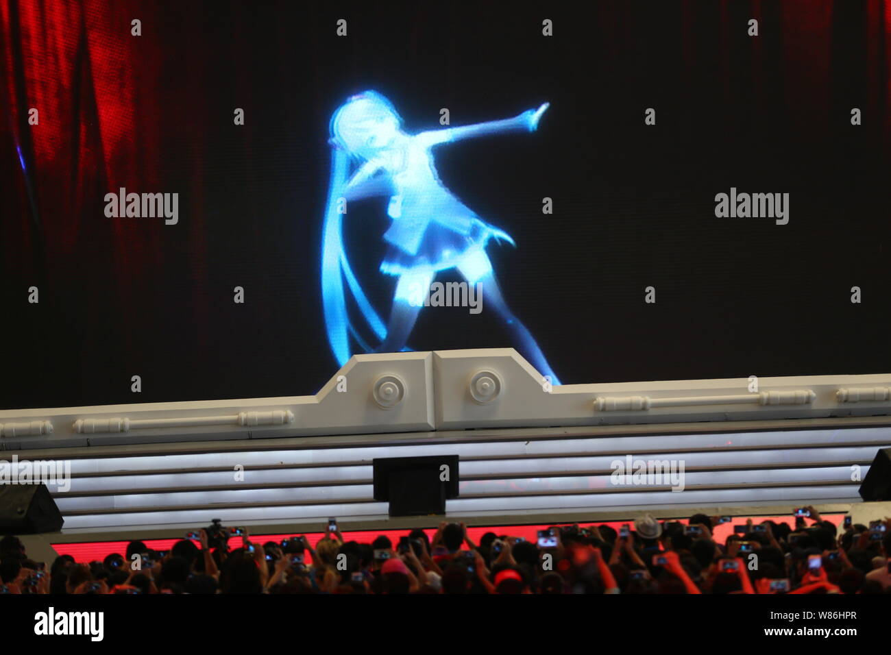 A crowd of visitors watch a performance of Hatsune Miku, a humanoid ...