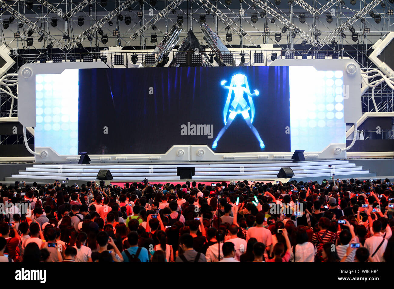 A crowd of visitors watch a performance of Hatsune Miku, a humanoid ...