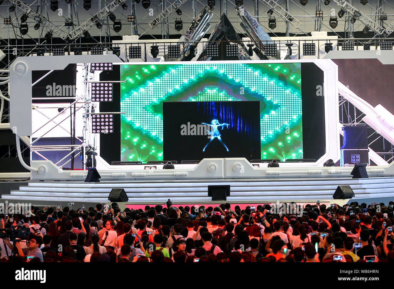 A crowd of visitors watch a performance of Hatsune Miku, a humanoid ...