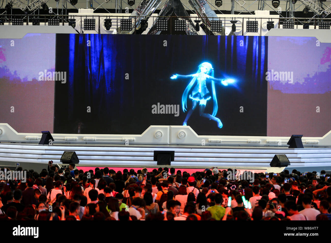 A crowd of visitors watch a performance of Hatsune Miku, a humanoid ...